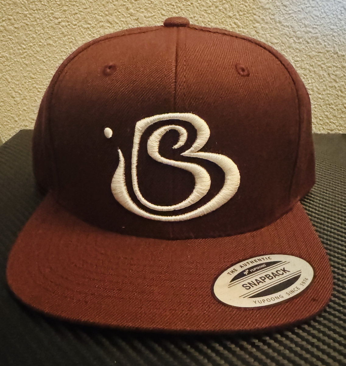 Burgundy hat with white logo. | BORED STIFF