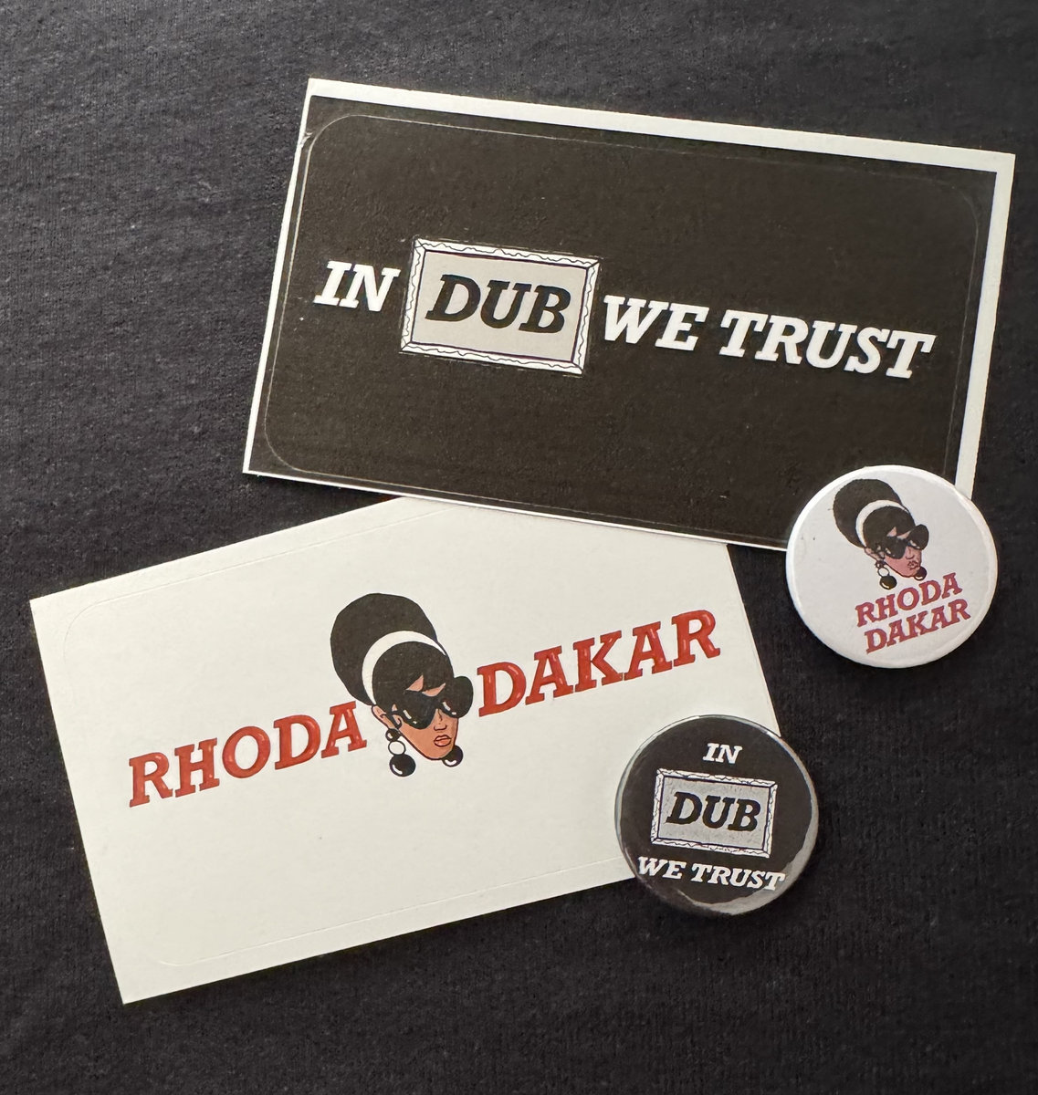 In Dub We Trust and Rhoda Dakar logo badges and stickers | Rhoda Dakar